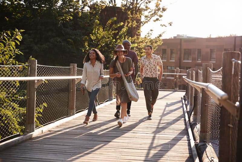 Group of Friends Walking Along Bridge in Urban Setting Stock Photo ...