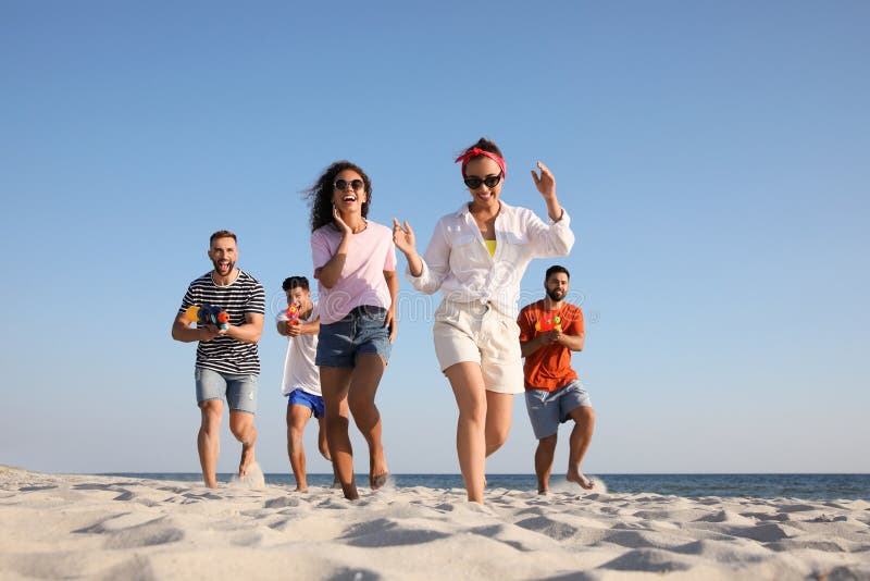 Group of Friends with Water Guns Having Fun on Beach Stock Photo ...