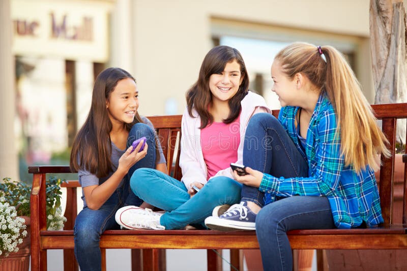 Group Of Girls Sitting In Mall Using Mobile Phones Stock Photo - Image ...