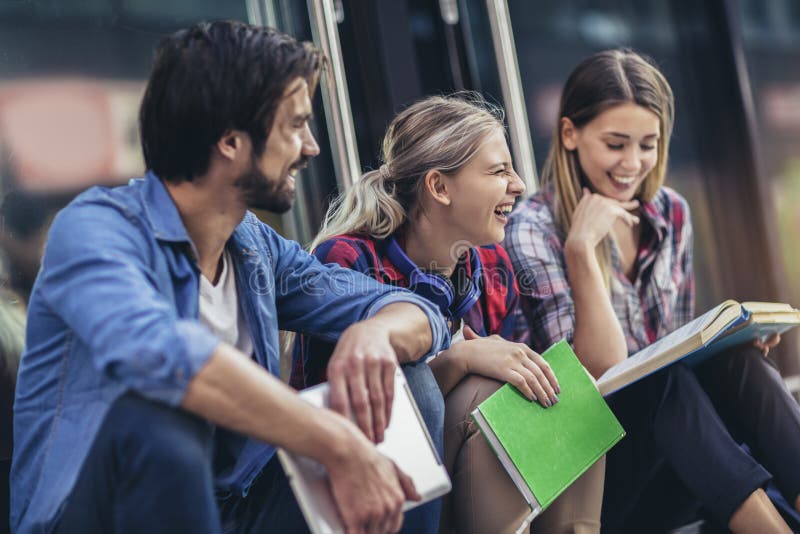 Happy University Students Talking while Sitting Outdoors at Campus ...