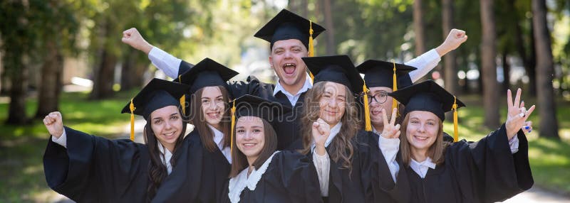 Group of Happy Young People in Graduation Gowns Outdoors. Students are ...
