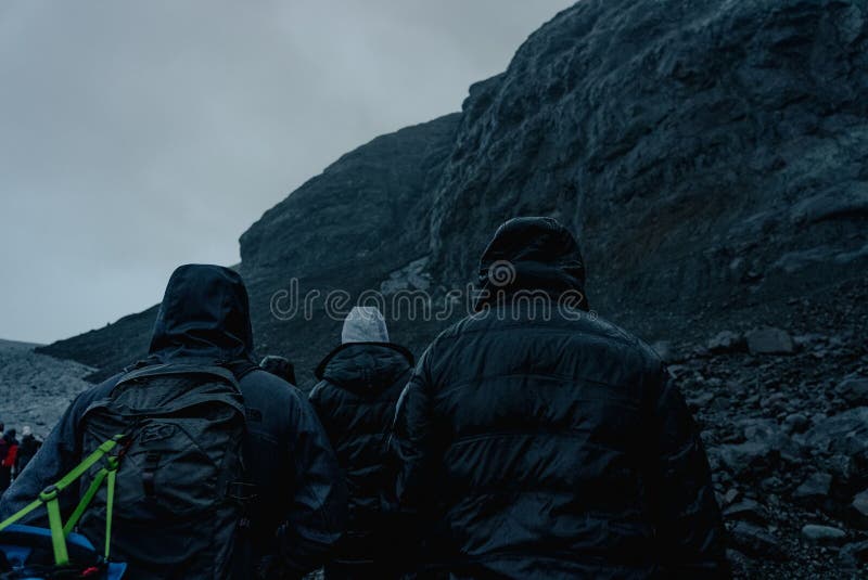 Group of Hikers in Black Jackets Climbing the Cliff. Stock Image ...
