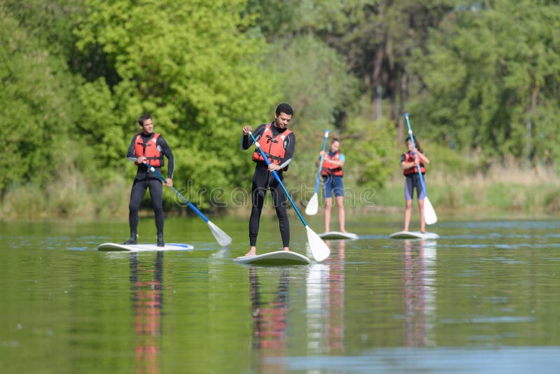 Group Holiday Maker Doing Stand Up Paddle Board Lesson Stock Photo ...