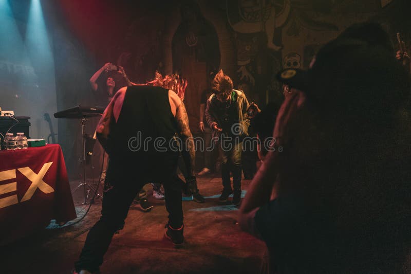 A Group of People Standing on Top of a Stage Next To a Red Table ...