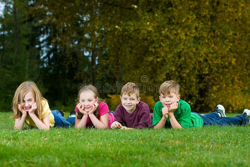 A Group of Kids Laying Down in the Grass Stock Image - Image of laying ...