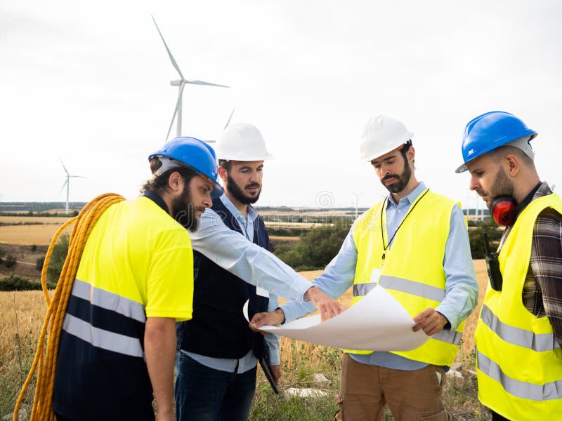 Group of Male Engineers and Workers Looking at Blueprints in a Field of Windmills Stock Image ...