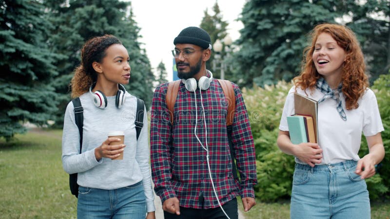 Group of Mates Walking Outdoors on Campus with Books and Coffee ...