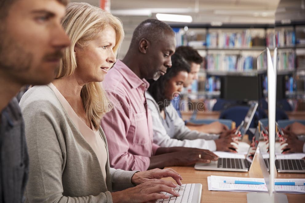 Group of Mature College Students Working on Computers in Library Stock ...