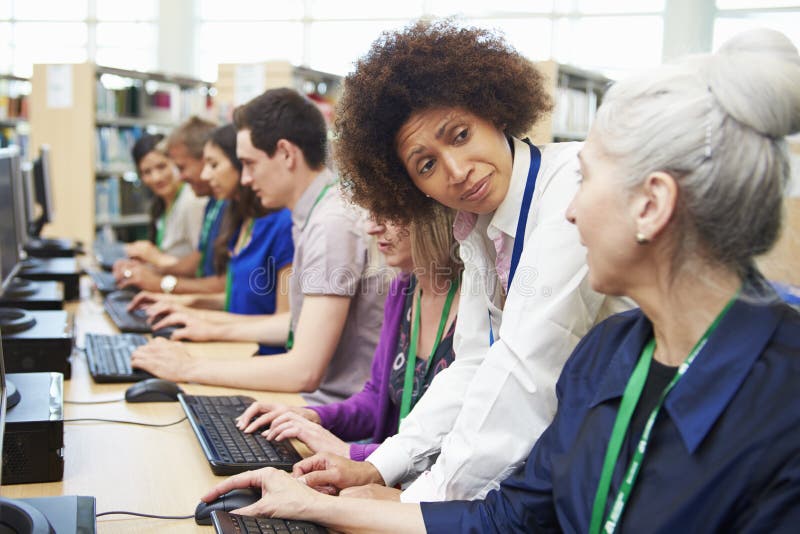 Group of Mature Students Working at Computers with Tutor Stock Photo ...