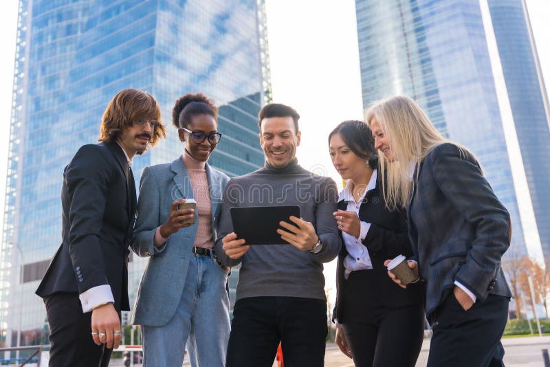 Group of Multi-ethnic People in a Business Park Looking at a Tablet ... Group of Multi-ethnic People in a Business Park Looking at a Tablet ...