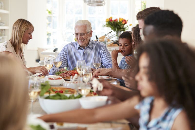 Group of Multi-Generation Family and Friends Sitting Around Table and ...