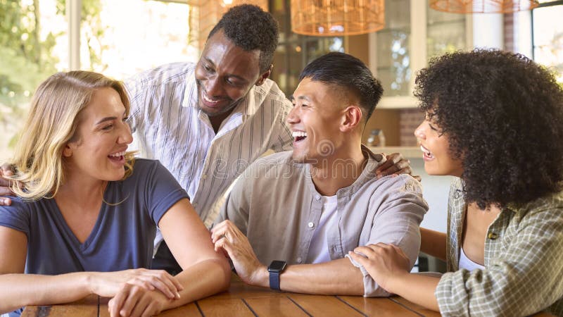 Group Multi-Racial Friends Sitting Around Table at Home Laughing and ...