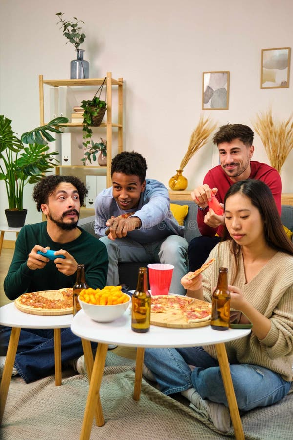 Group of Multiracial Friends Eating Pizza and Playing Video Games at ...