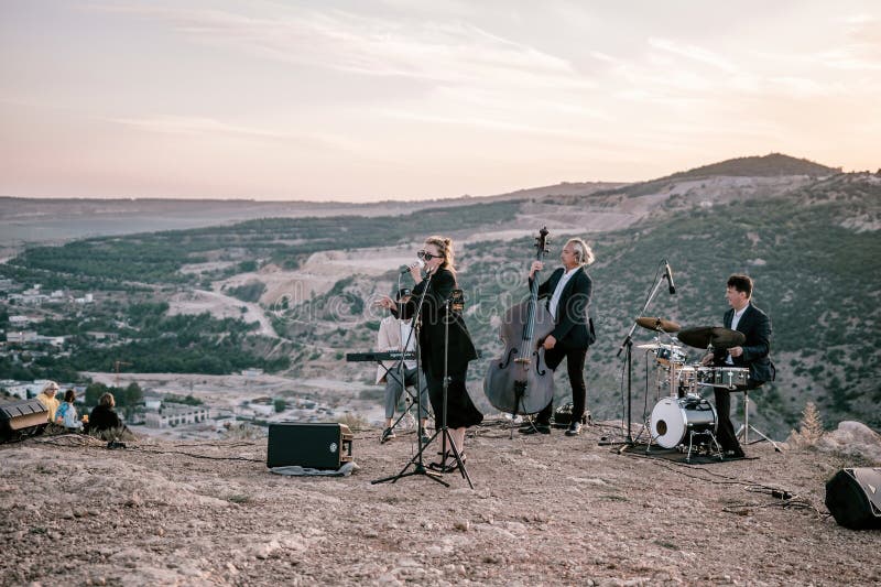 A Group of Musicians are Playing Instruments on a Hillside. the Sun is ...