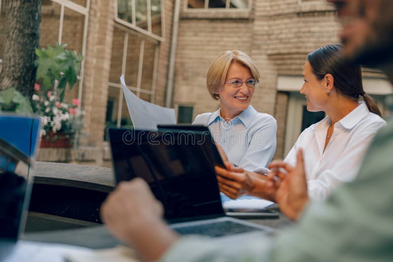Creative Team Collaborating on Project during Meeting in Outdoor Cafe ...