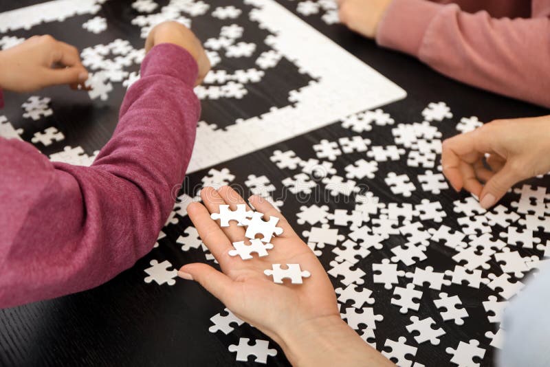 Group of People Assembling Puzzle on Dark Table Stock Photo - Image of ...