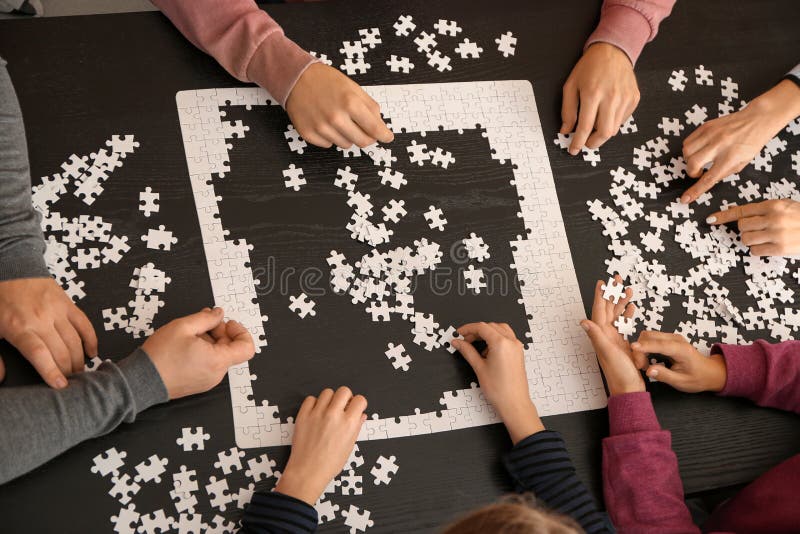 Group of People Assembling Puzzle on Dark Table Stock Image - Image of ...