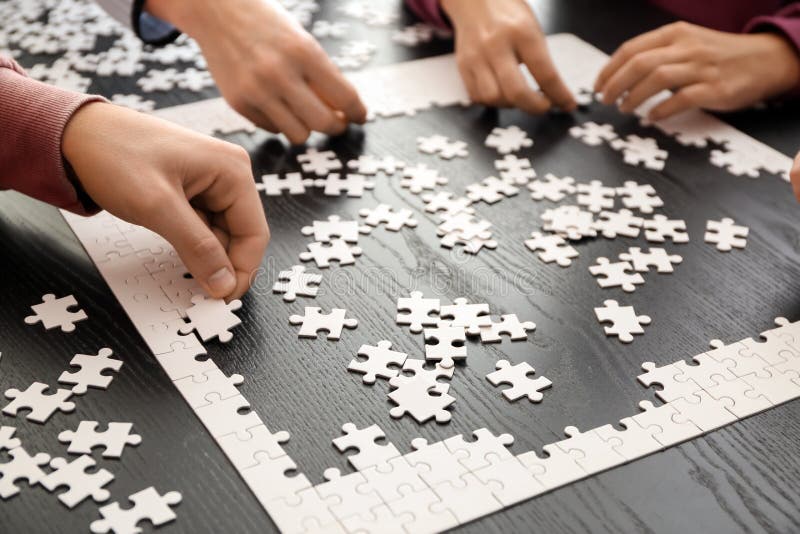 Group of People Assembling Puzzle on Dark Table Stock Image - Image of ...