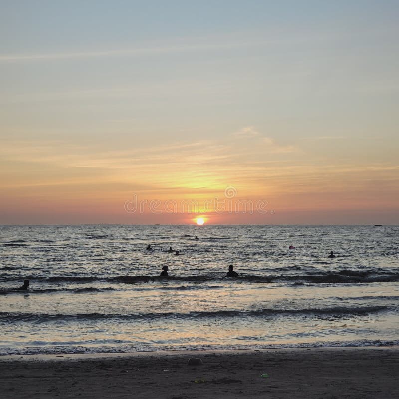 A Group of People Bathing on the Beach while Watching the Sunset ...