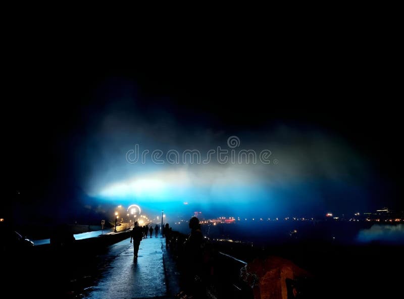 Several People are Standing Around a Fire and Water Fountain at Night ...