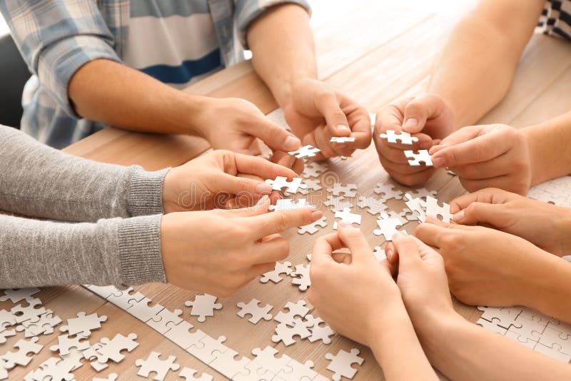Group of People Holding Pieces of Puzzle Over Wooden Table Stock Photo ...