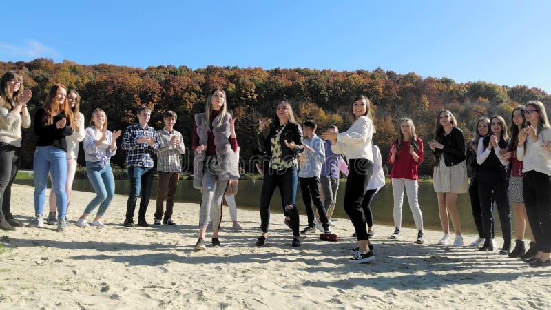 Group of People on the Sandy Beach of the Lake Performs Various Dances ...