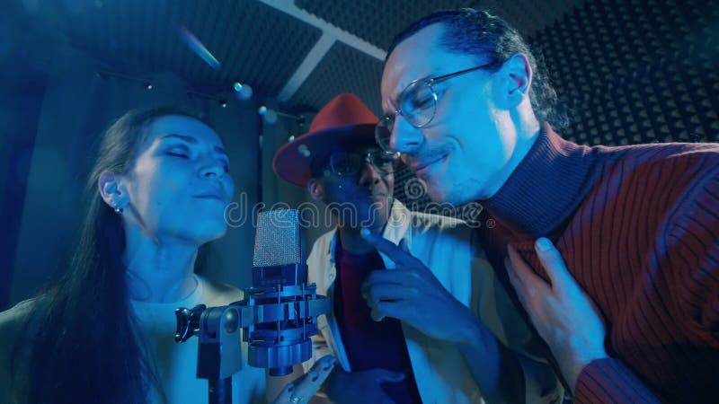 A Group of People are Singing into a Studio Microphone in a Close Up ...