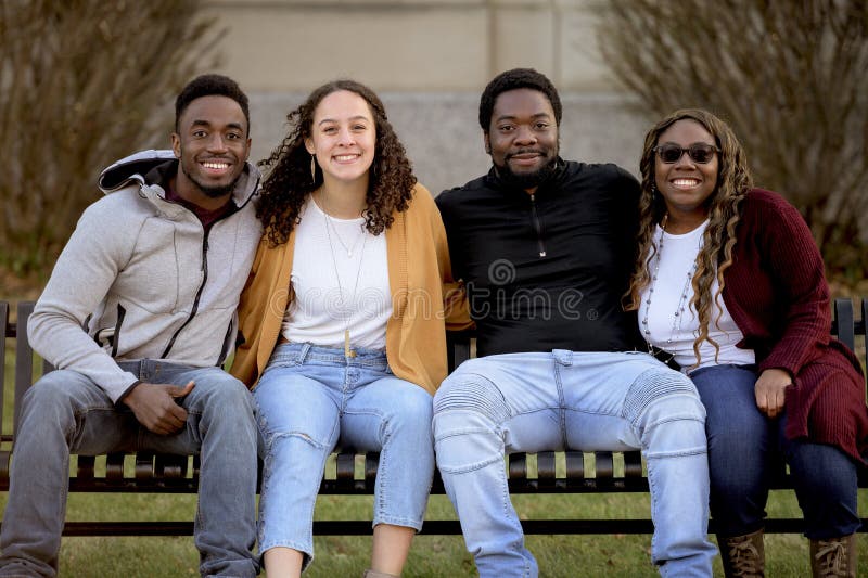 Group of People Sitting on a Bench in a Park Under Sunlight with a ...