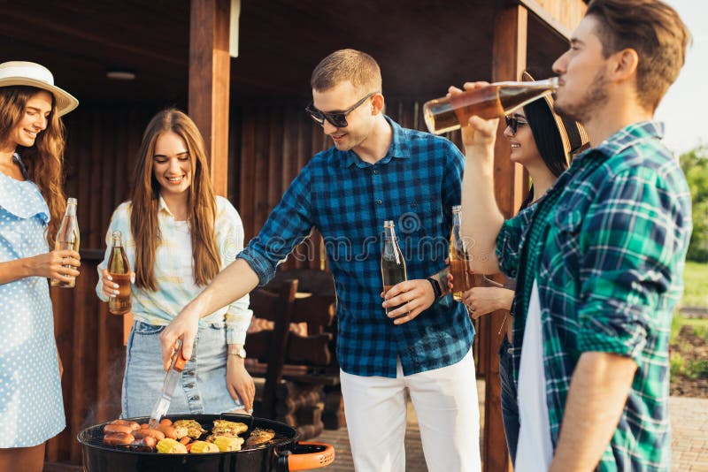 Group of People Standing Around a Barbecue, Grilling Outdoors, Chatting ...