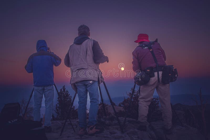 Group of People Standing Atop a Mountain Taking Pictures of the Setting ...