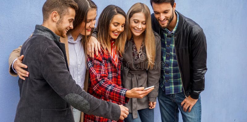 Group of People Standing by the Wall and Sharing Online Stuff- Friends ...
