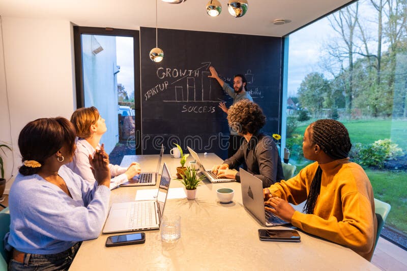A Group of People are at a Table Talking and Using Laptops Stock Photo ...