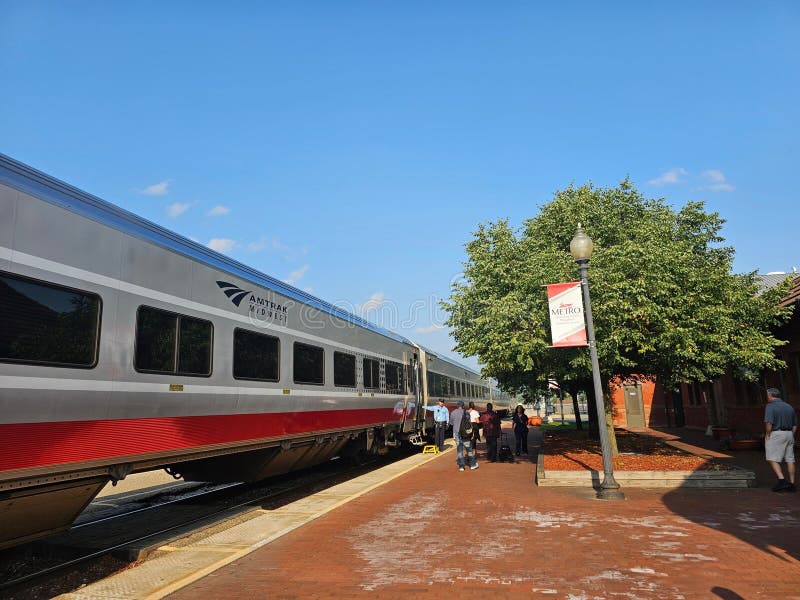 Group of People Walking Along the Platform of a Train Station, with a ...