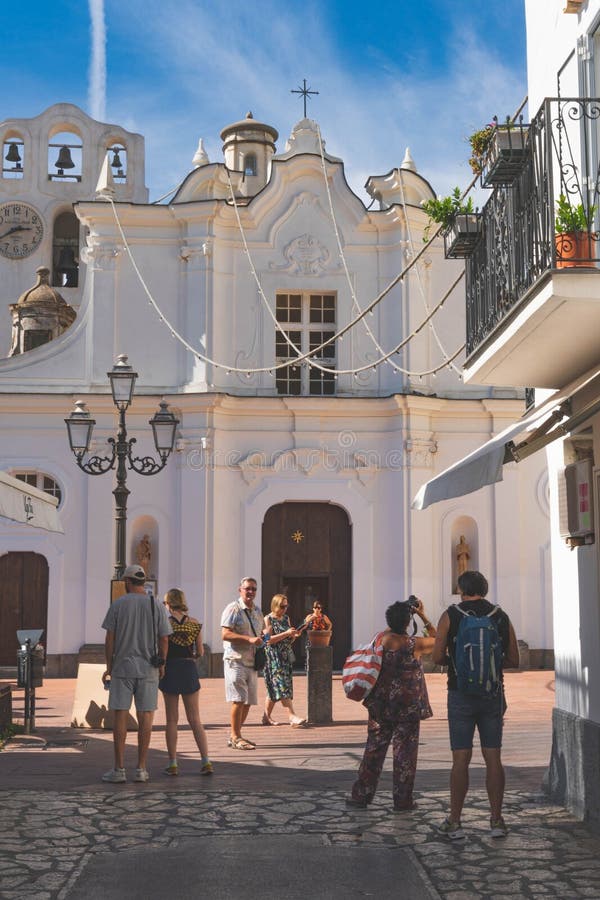 Group of People Walking Around Outside a Building with a Clock ...