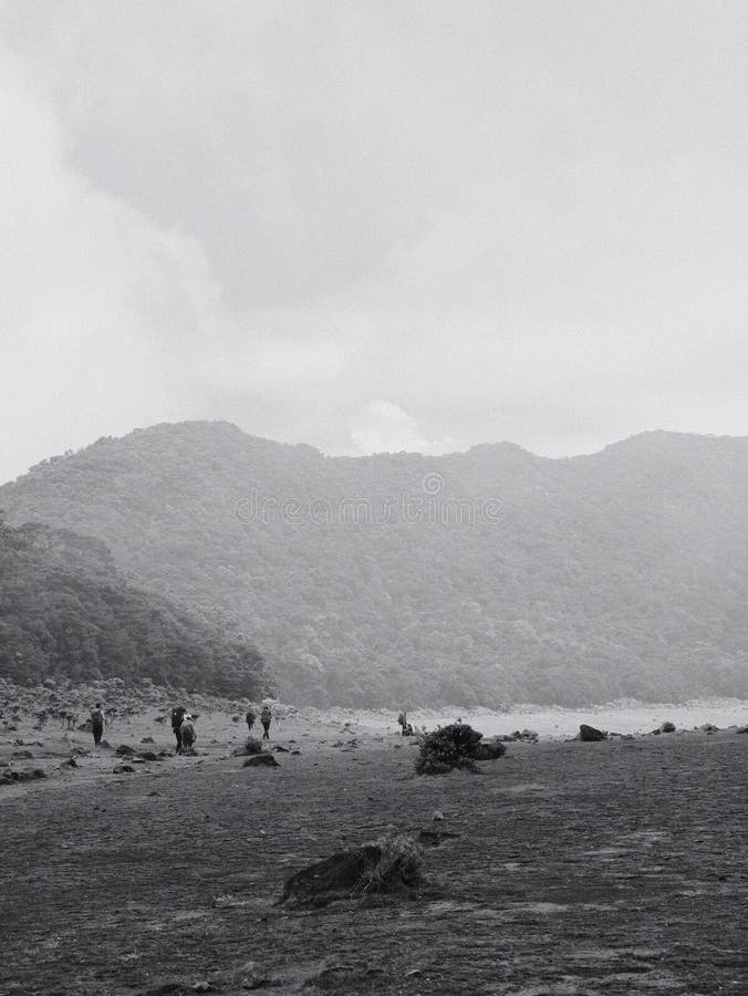 A Group of People are Walking on a Beach Near a Mountain Stock Photo ...