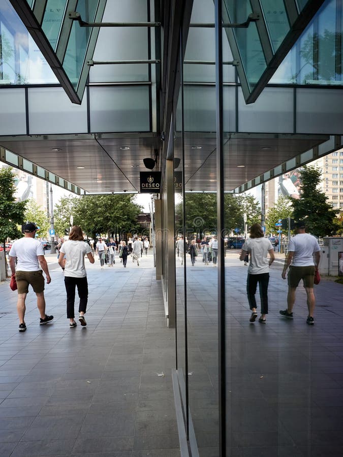Group of People Walking Down a Sidewalk in Front of a Building ...