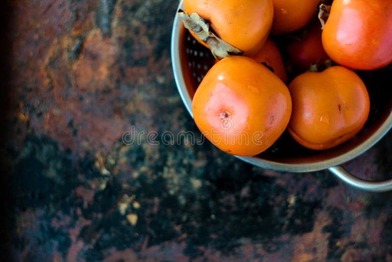 Group of Persimmons in Metal Collander Over Rustic Surface. Stock Image ...