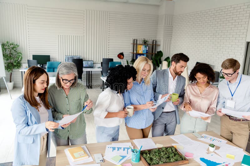 Group of Professionals Discussing Documents during a Team Meeting in a ...