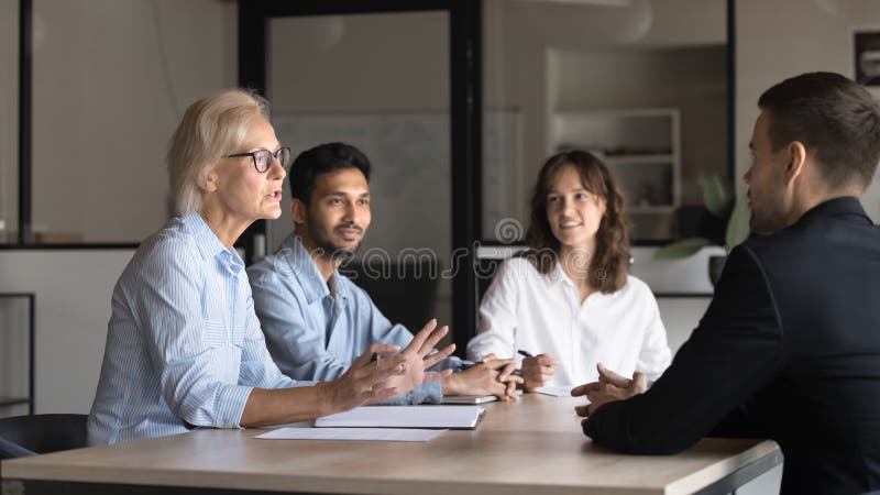 Group of Professionals Sit Around Conference Table Engaged in ...