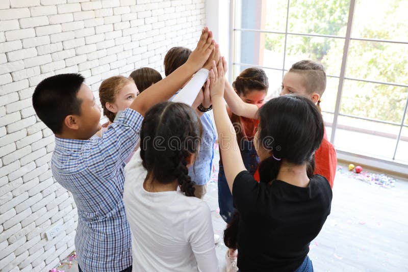 Group of School Kids Stacking Hands in Classroom Education Concept ...
