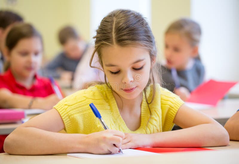 Thoughtful Young Schoolgirl in Classroom Writing Stock Image - Image of ...