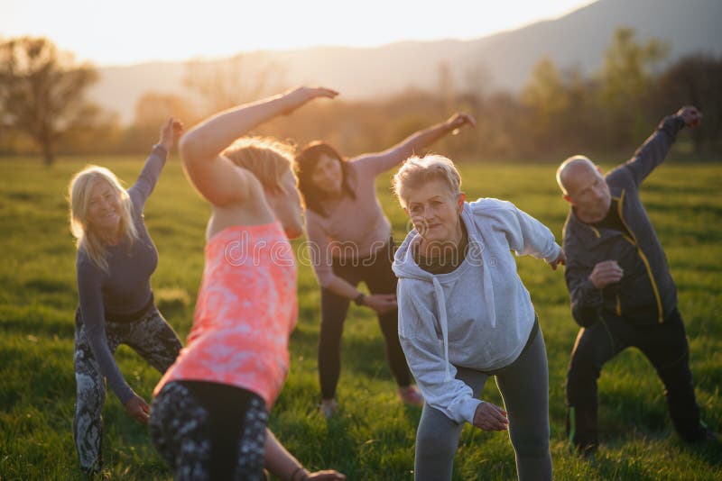 Group Of Seniors With Sport Instructor Doing Exercise Outdoors In ...