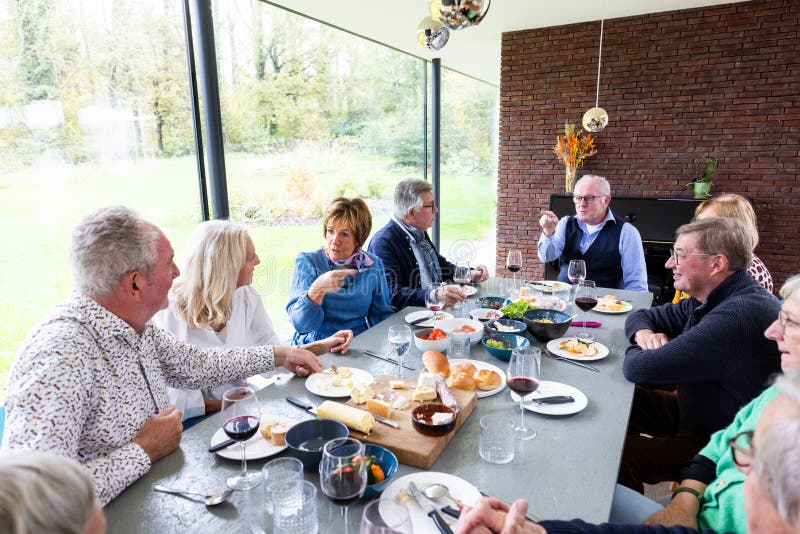 Group Sharing Food at a Table in a Building, by a Window, Having Fun at ...