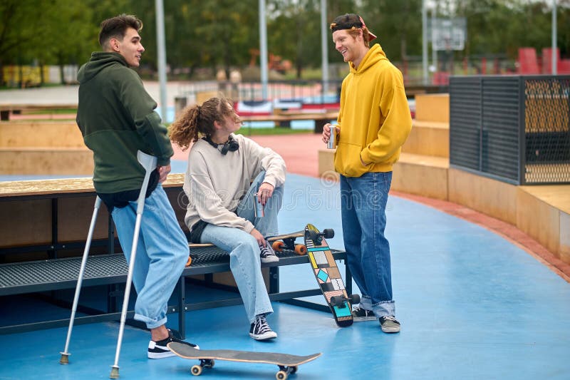 Group of Skateboarders Sitting on the Bench in the Park and Talking ...