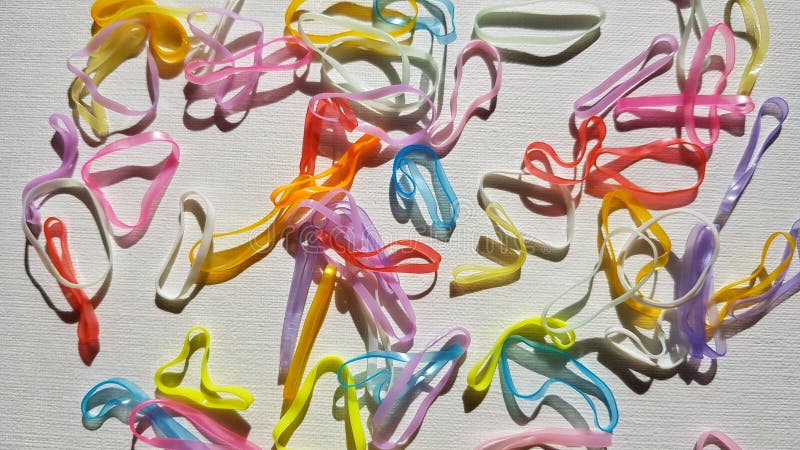 Group of Small Multi-colored Elastic Bands for Hair on a White Table ...