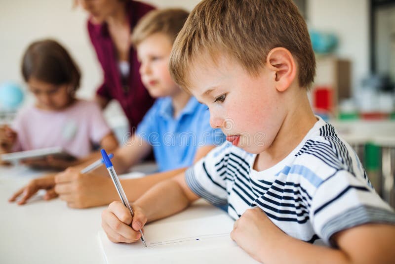 A Group of Small School Kids with Teacher in Class Writing. Stock Photo ...
