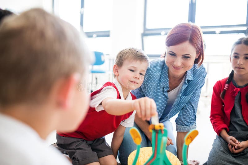 A Group of Small School Kids with Teacher Sitting on the Floor in Class ...