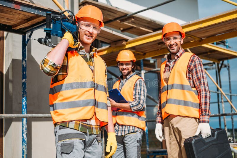 Group of Smiling Builders with Building Equipment Standing at ...