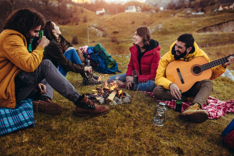Smiling Friends Sitting Around Bonfire in Camping Stock Photo - Image ...