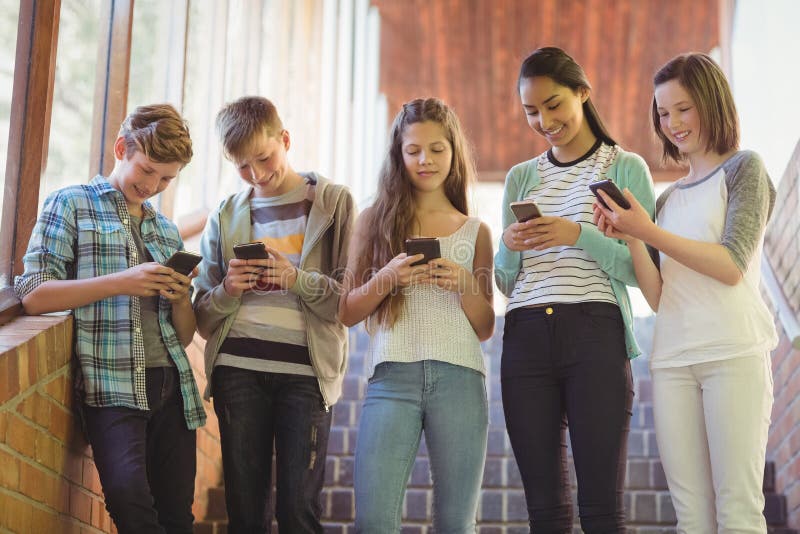 Group of Smiling School Friends Using Mobile Phone in Corridor Stock ...